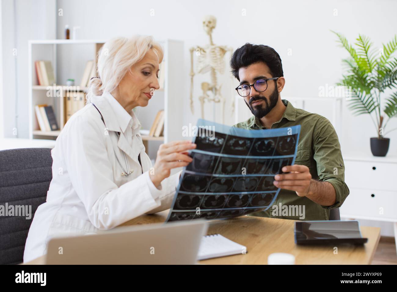 Skilled radiologist in white uniform explaining visible changes on x ...