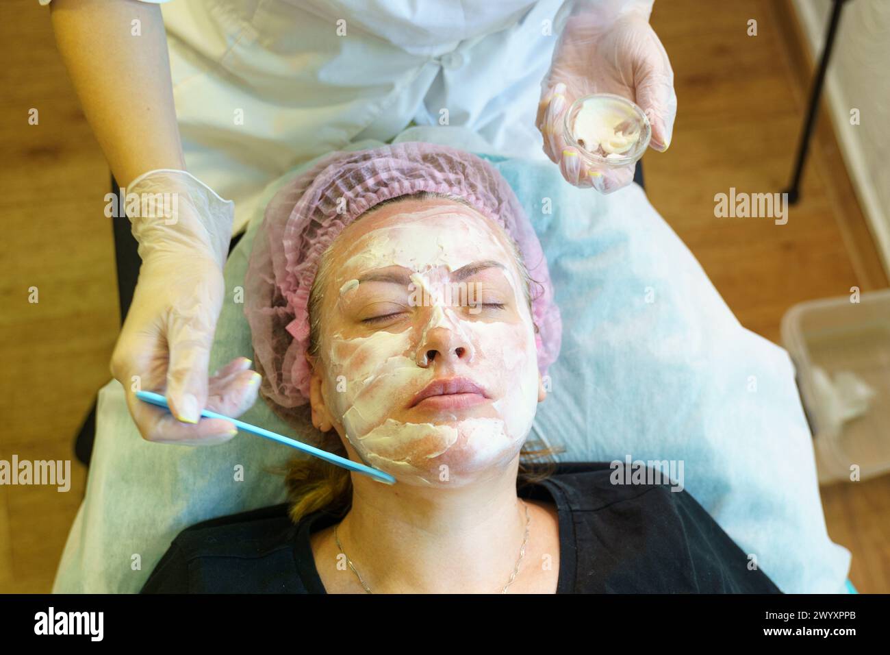 A woman is having a facial mask applied to her face at a spa or beauty ...