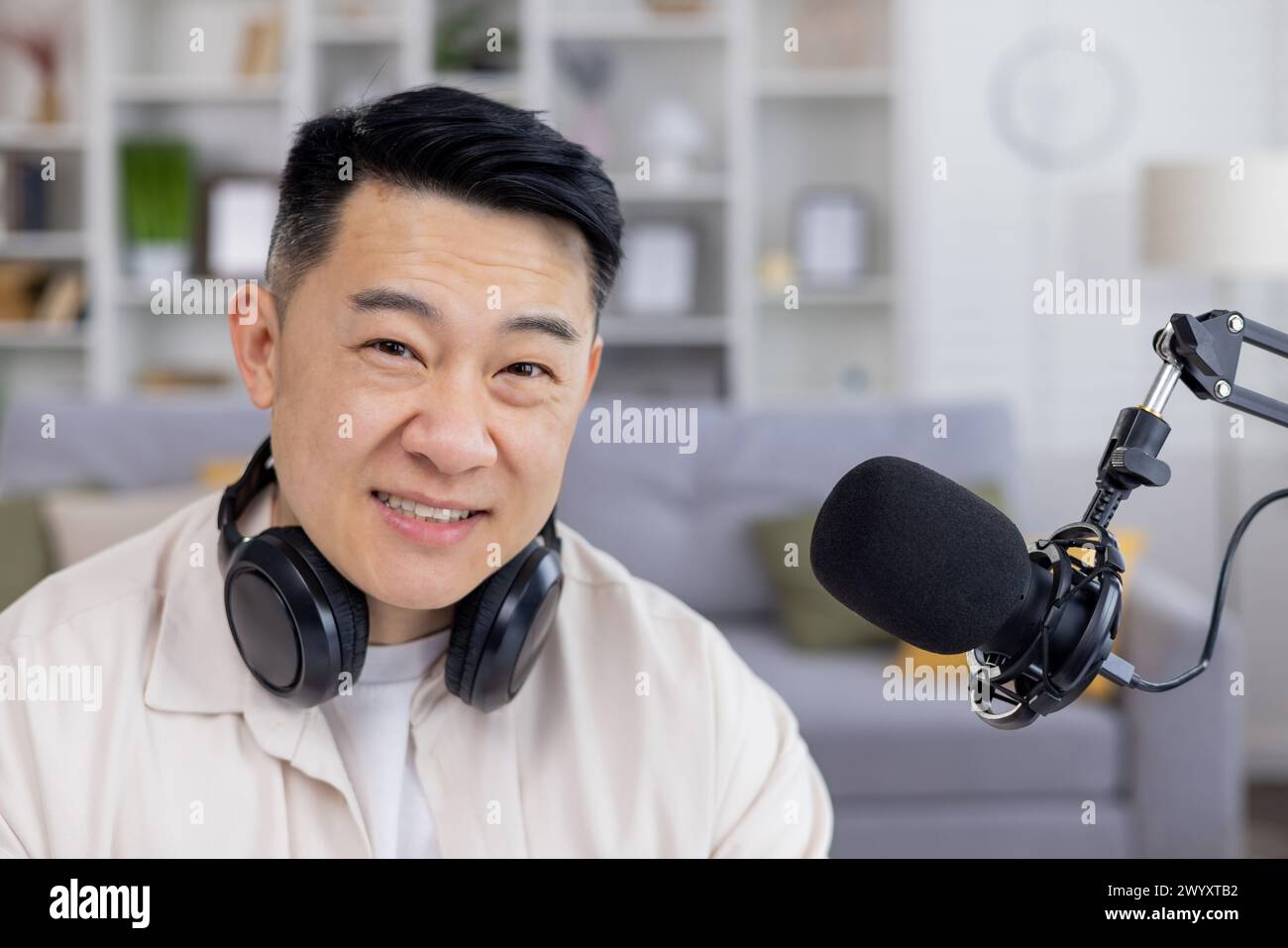 Cheerful male podcaster with headphones speaks into a microphone ...