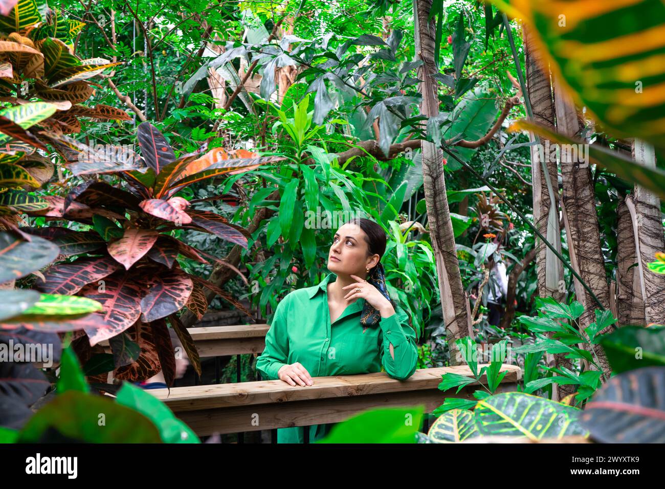 Woman observing nature with her arm resting on the railing of a bridge ...