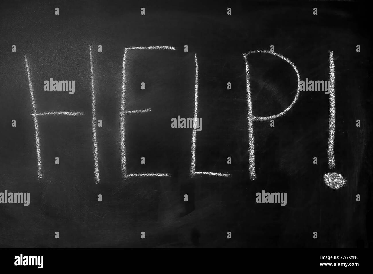 Word "help" with an exclamation written with white chalk on a black ...