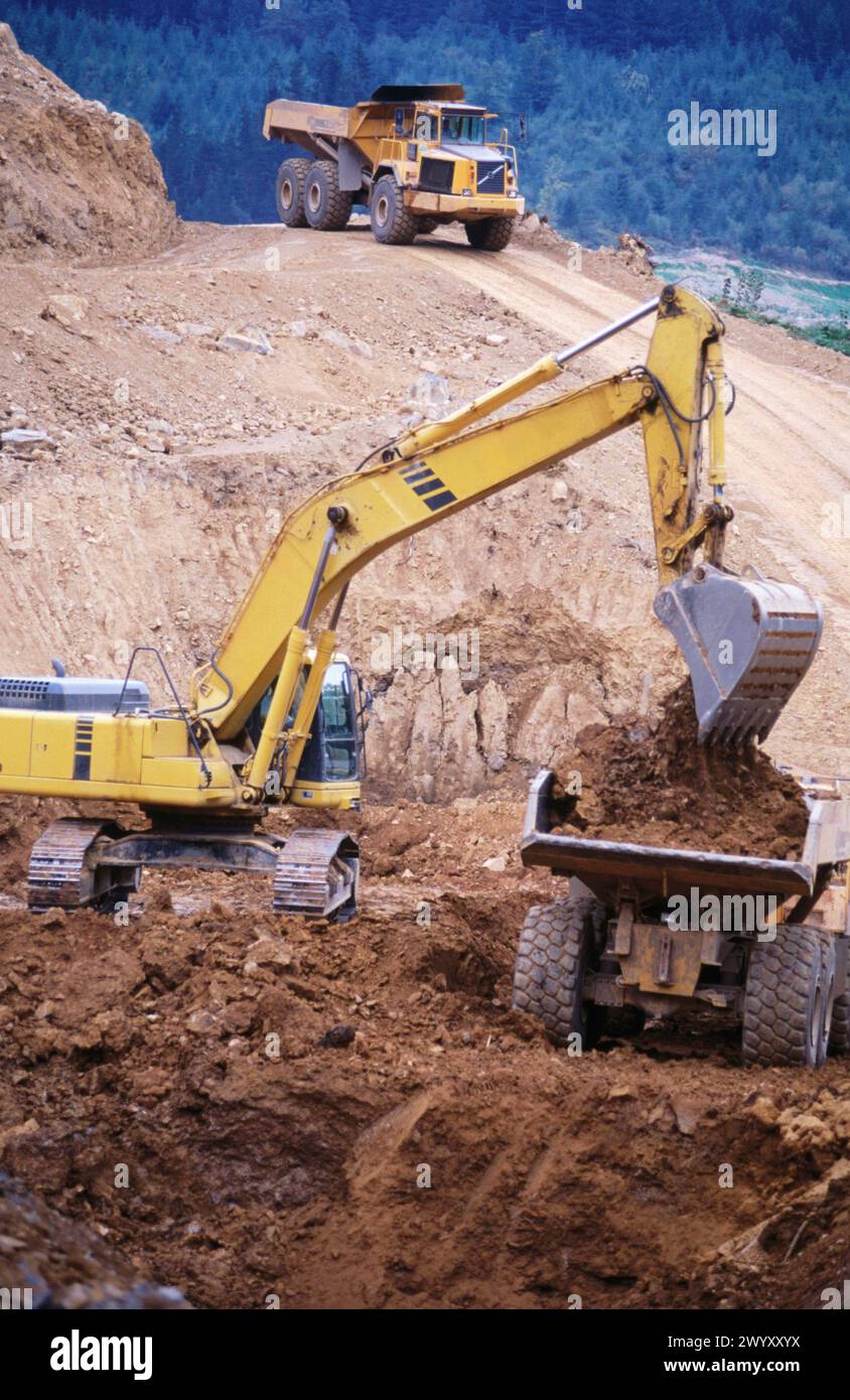 Excavator at construction site, loading truck Stock Photo - Alamy
