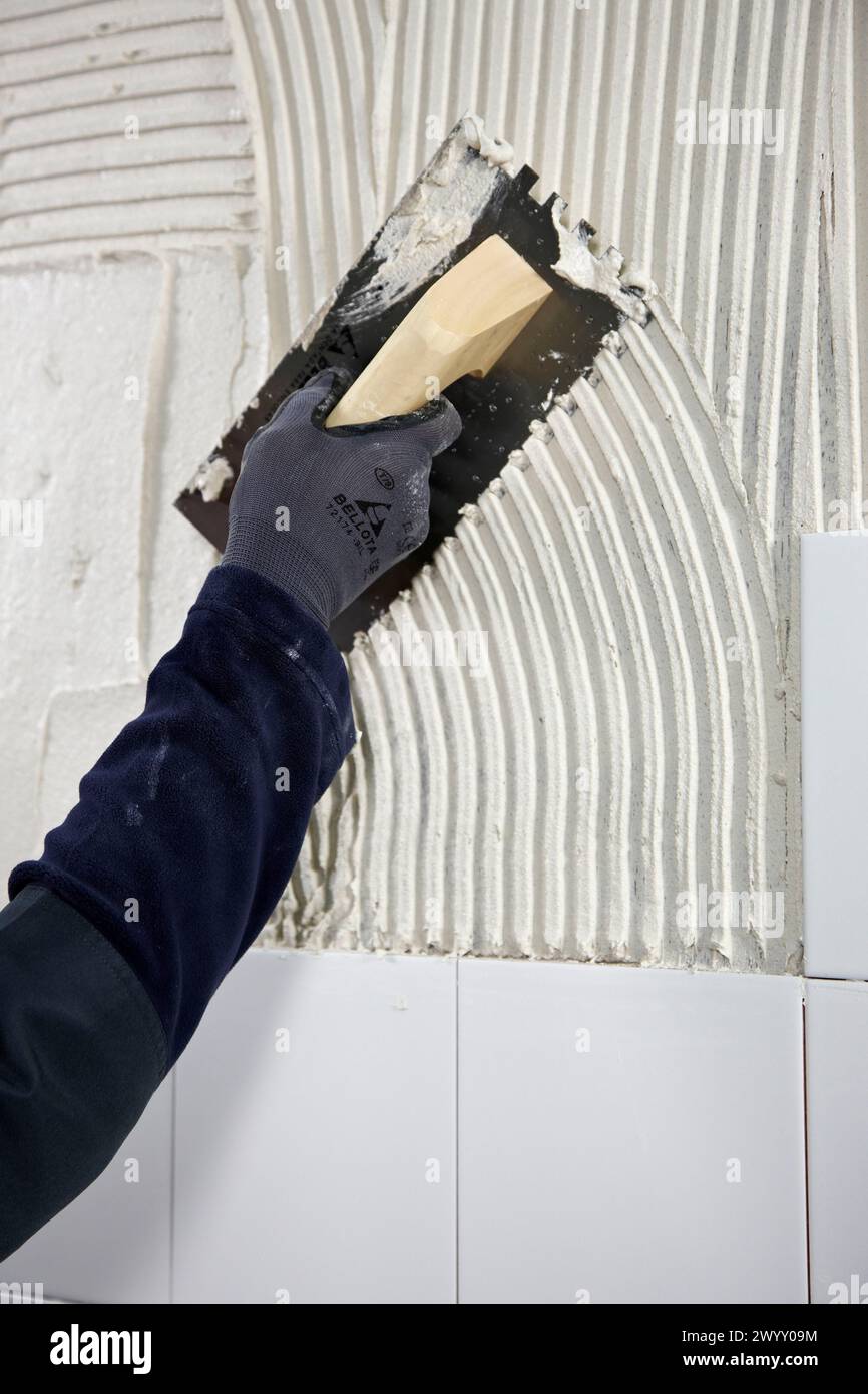 Preparing wall with glue mortar before tiling using a serrated ...