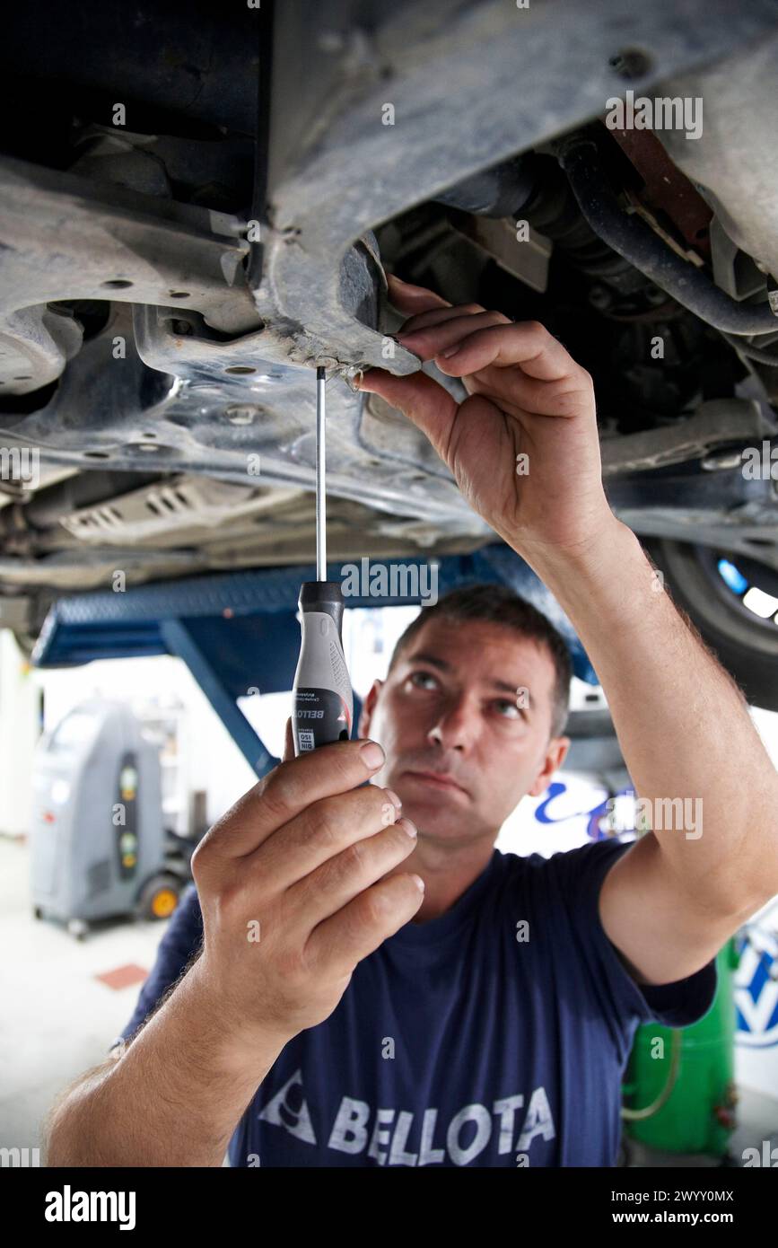 Worker using screwdriver in car repair shop Stock Photo - Alamy