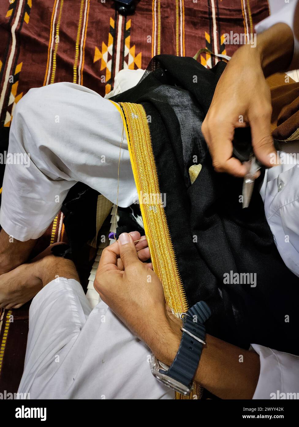 Close up shot of how the tailor are making a bisht, in Arabic cloak for ...
