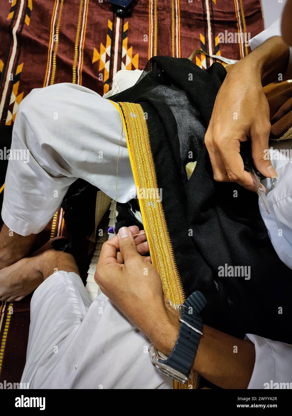 Close up shot of how the tailor are making a bisht, in Arabic cloak for ...