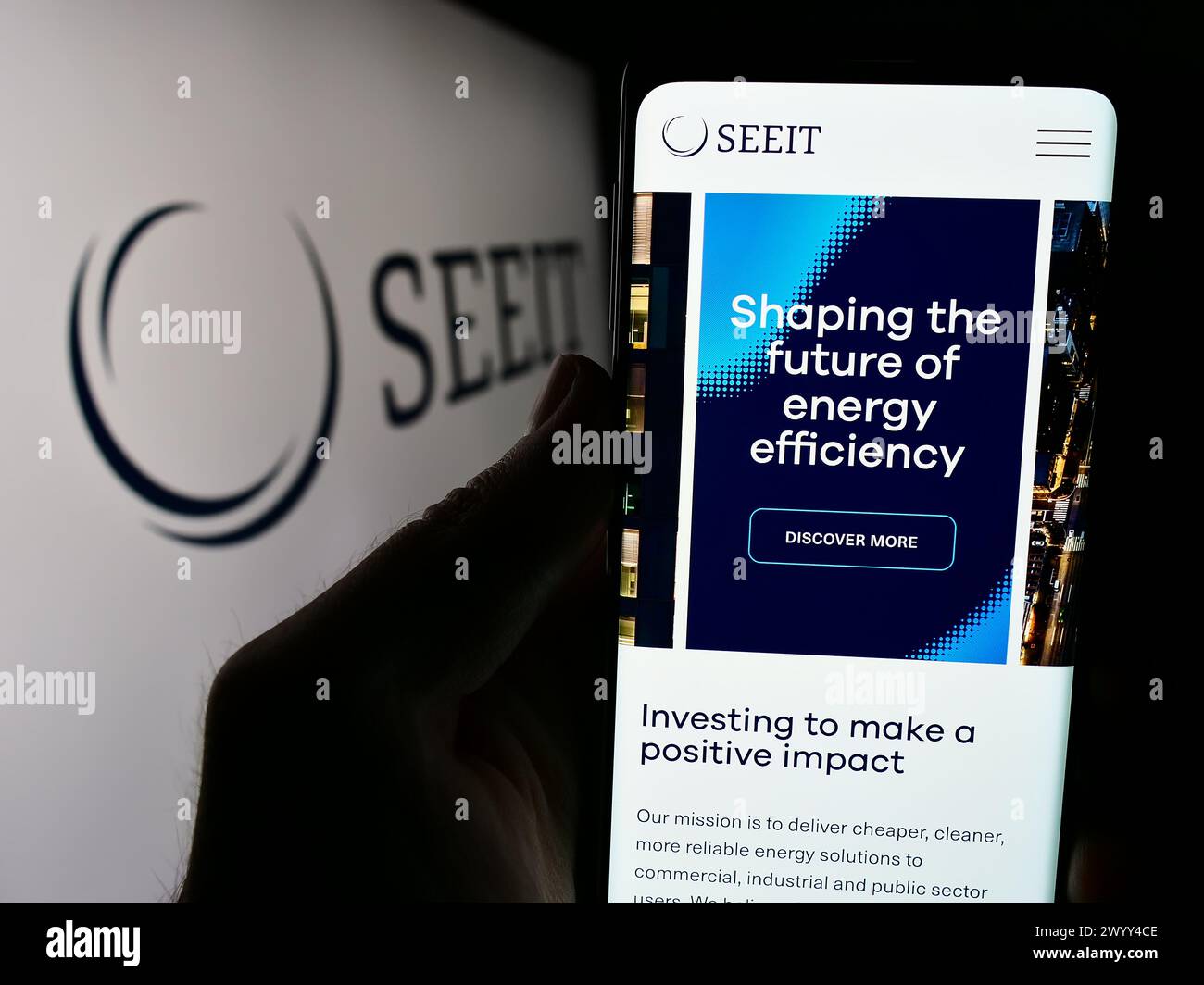 Person holding cellphone with webpage of company SDCL Energy Efficiency ...