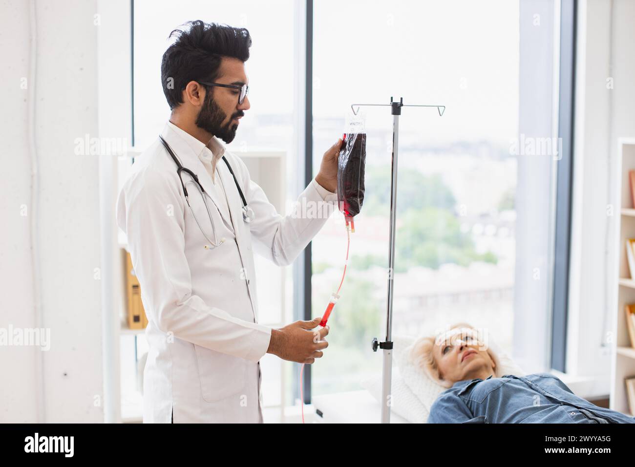 Elderly woman making blood transfusion looking at medical doctor in lab ...
