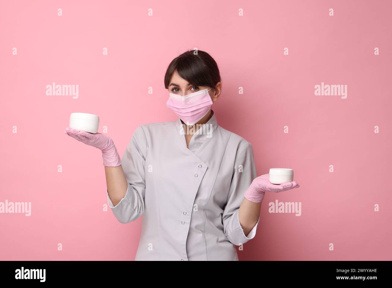Cosmetologist with cosmetic products on pink background Stock Photo - Alamy