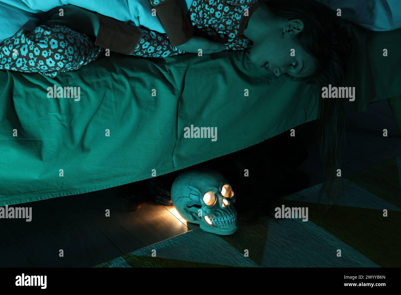 Childhood phobia. Girl looking at skull under bed indoors Stock Photo ...