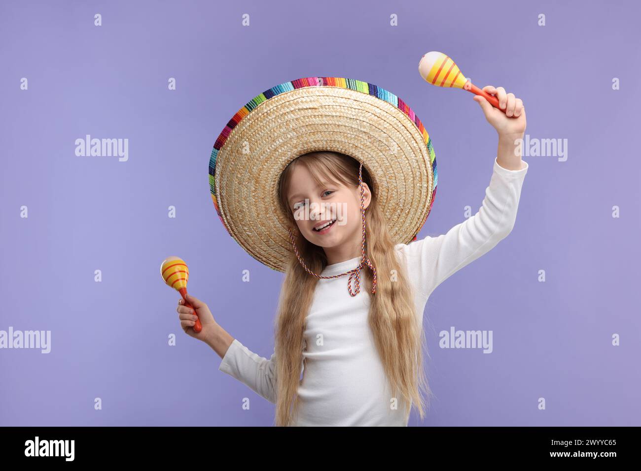 Cute girl in Mexican sombrero hat dancing with maracas on purple ...