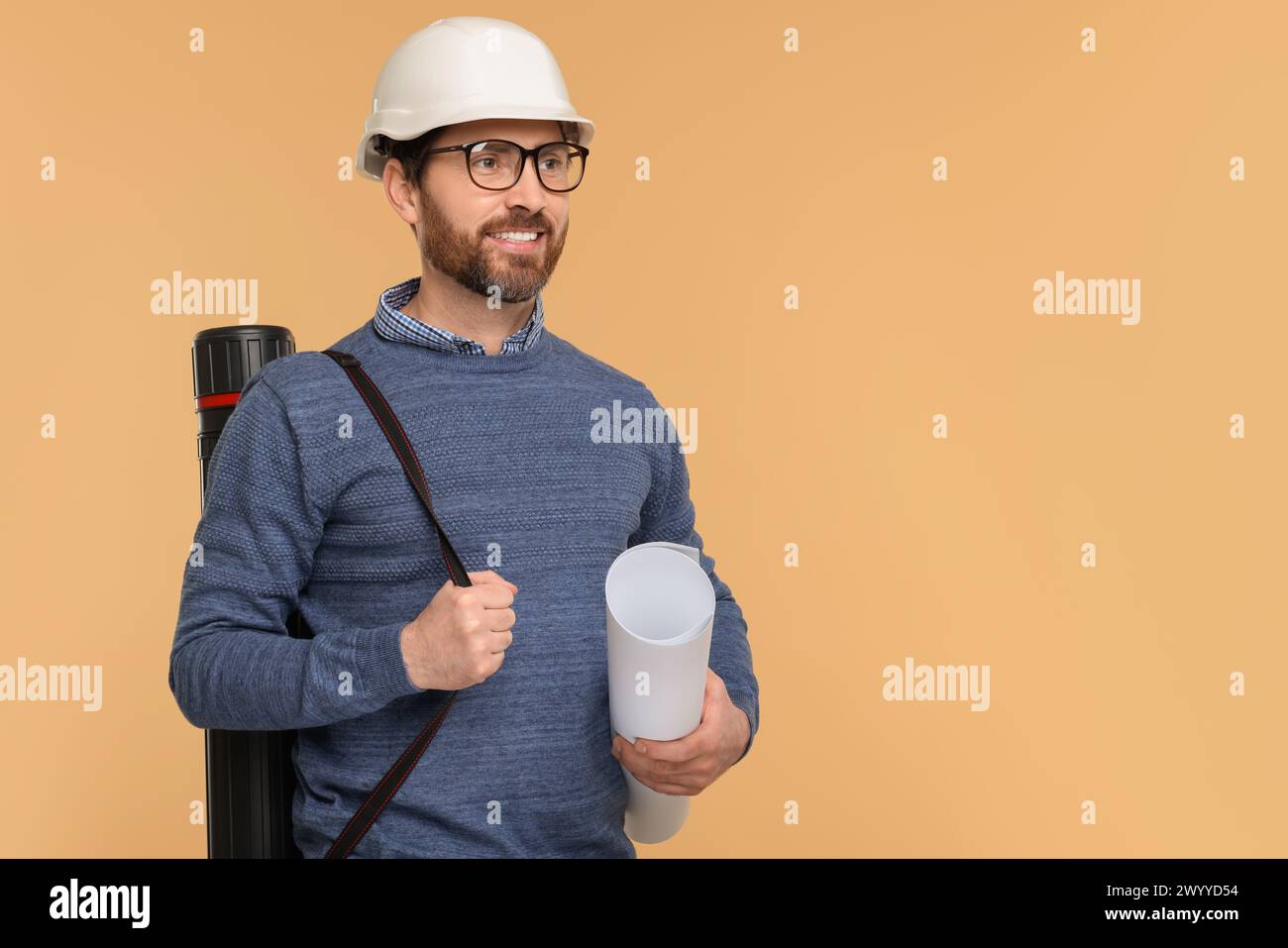 Architect in hard hat with drawing tube and draft on beige background ...