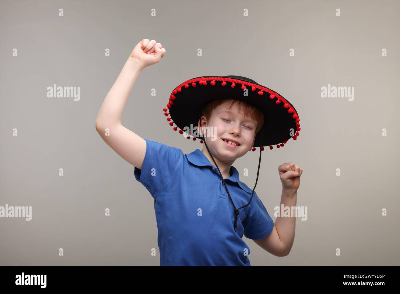 Cute boy in Mexican sombrero hat dancing on grey background Stock Photo ...