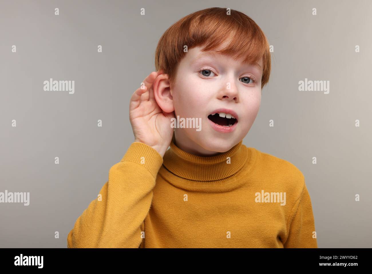 Little boy with hearing problem on grey background Stock Photo - Alamy