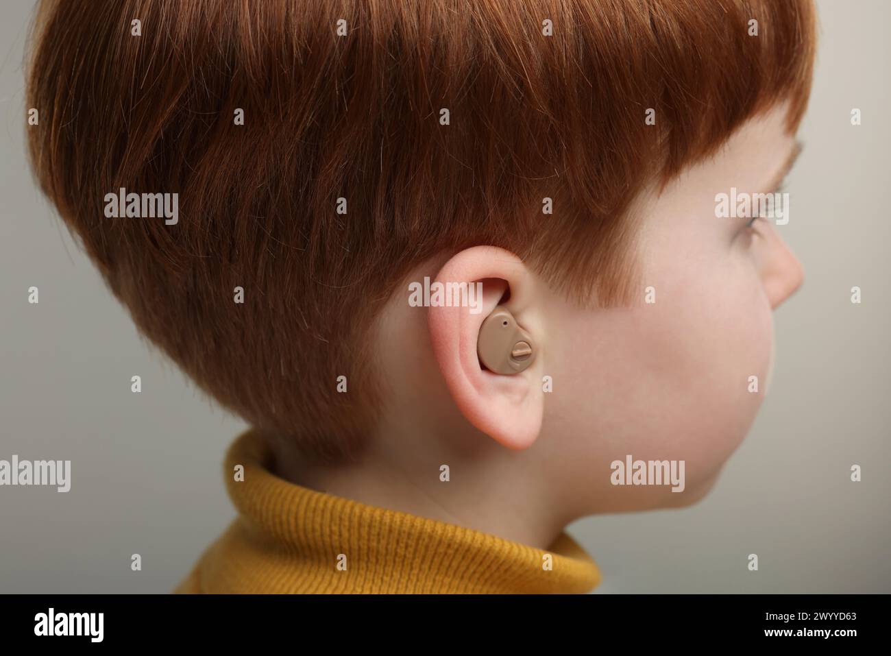 Little boy with hearing aid on grey background, closeup Stock Photo - Alamy