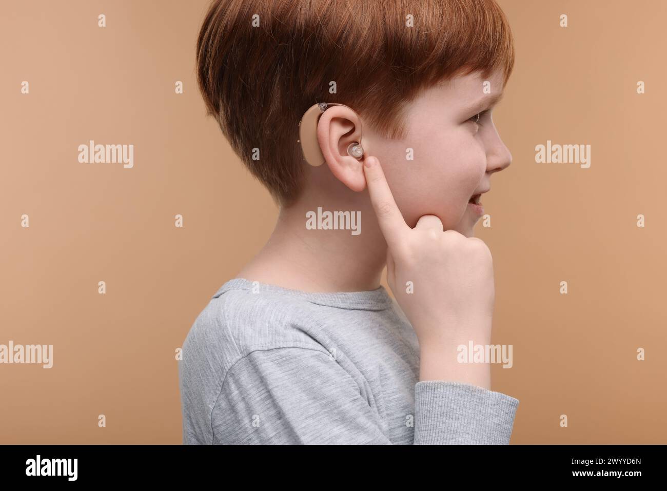Little boy with hearing aid on pale brown background, closeup Stock ...