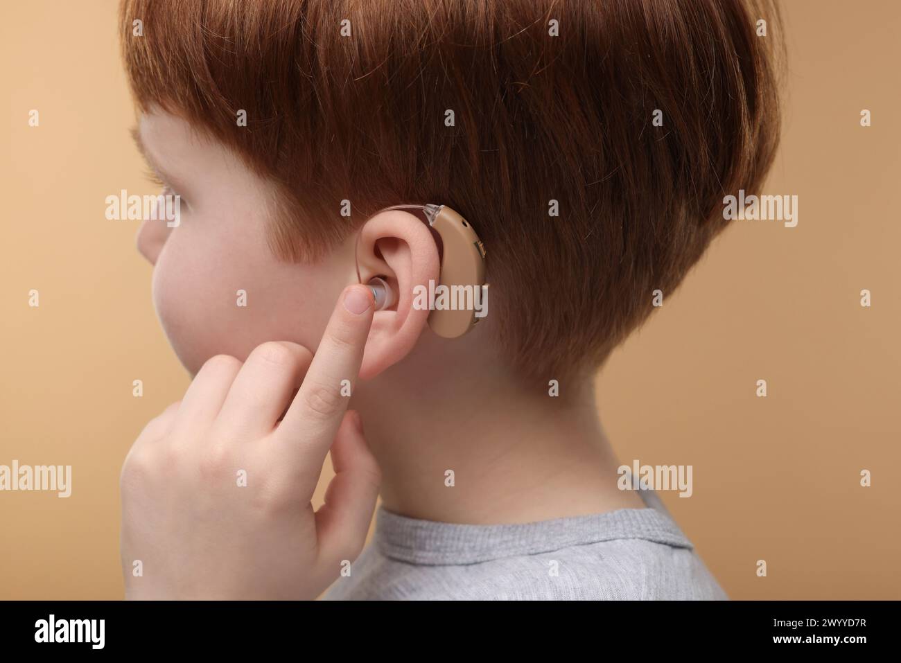 Little boy with hearing aid on pale brown background, closeup Stock ...