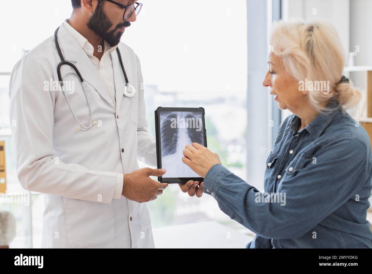 Skilled radiologist in white uniform explaining visible changes on x ...