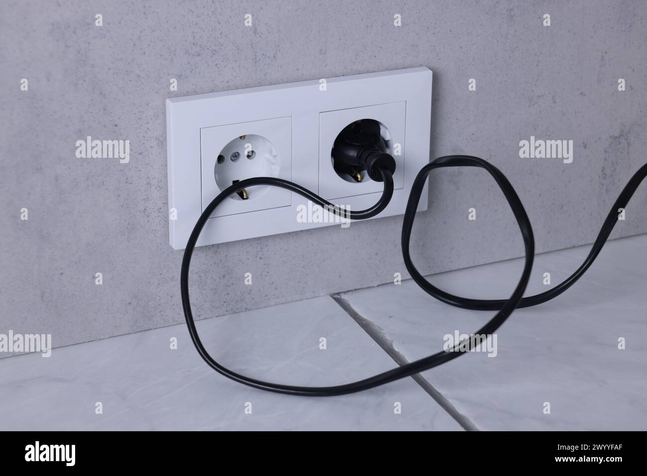 Power sockets and electric plug on grey wall Stock Photo - Alamy