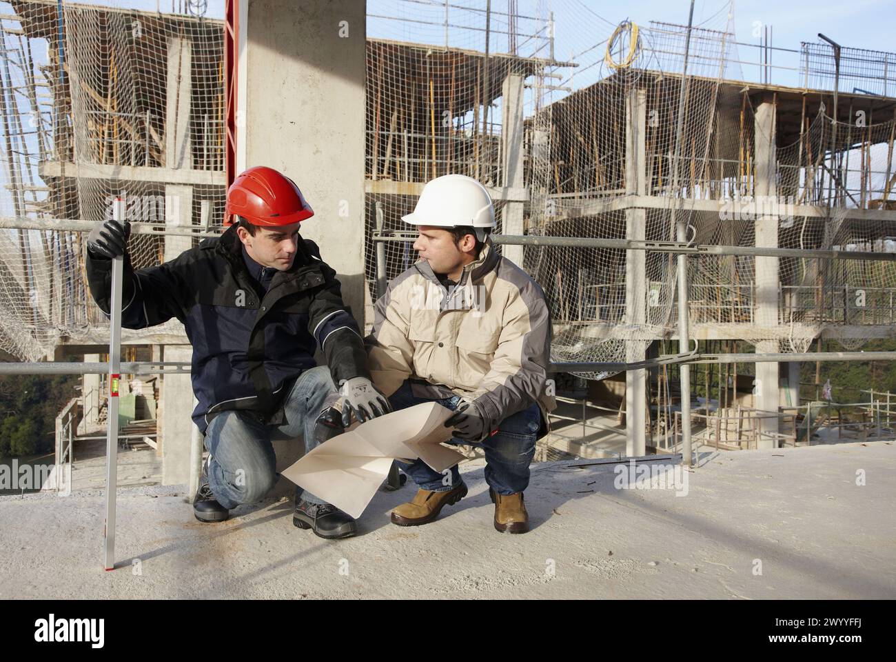 Architect and construction worker looking at blueprints, personal ...