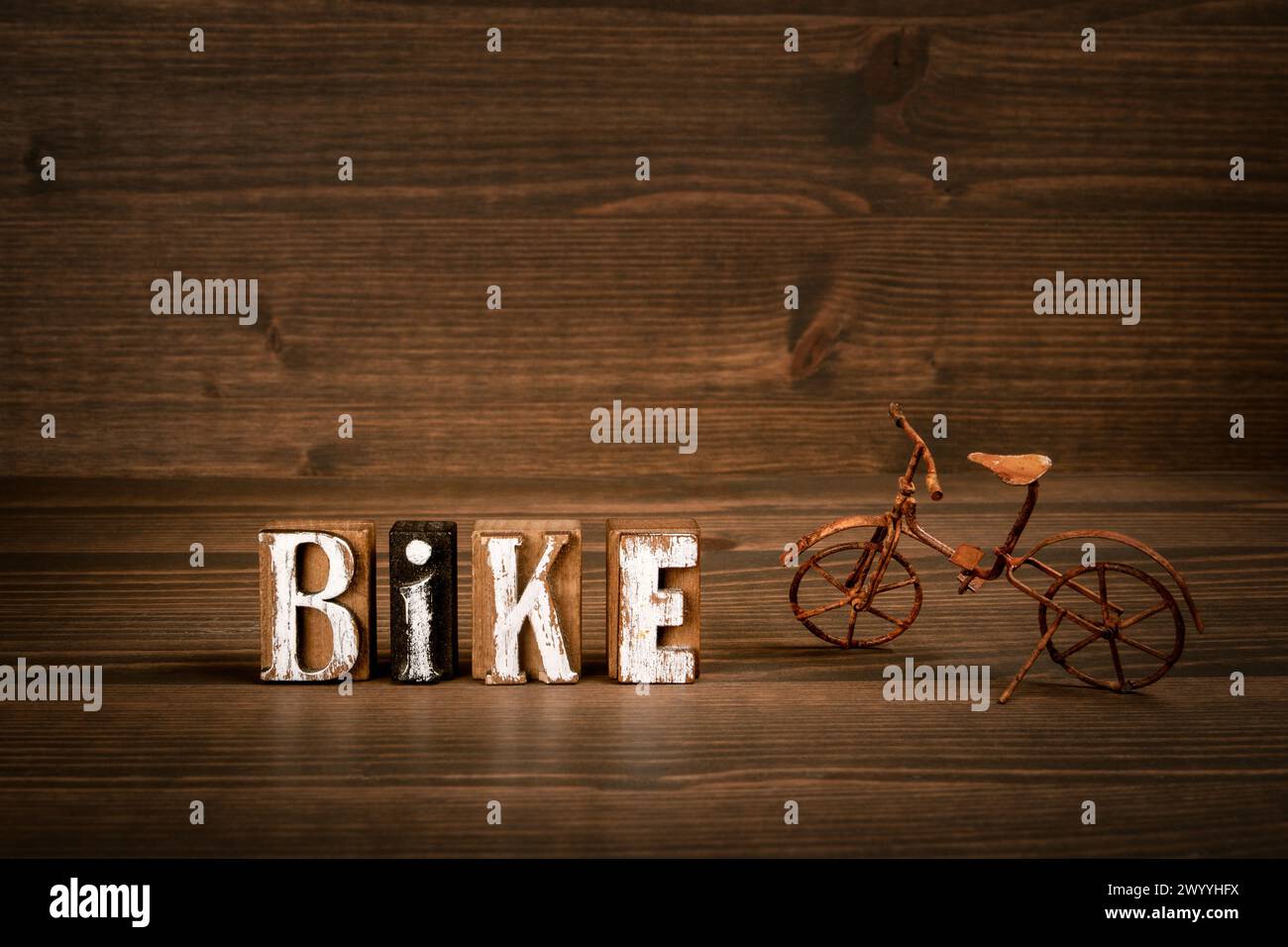BIKE. Text from alphabet blocks and rusty miniature bicycle on wood ...