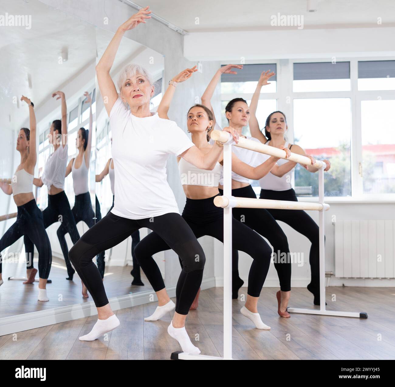Girls in ballet class perform composition with grand plie with ...