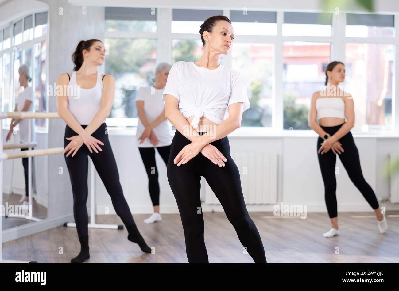 Young woman in group lesson with students rehearses, practices ballet ...
