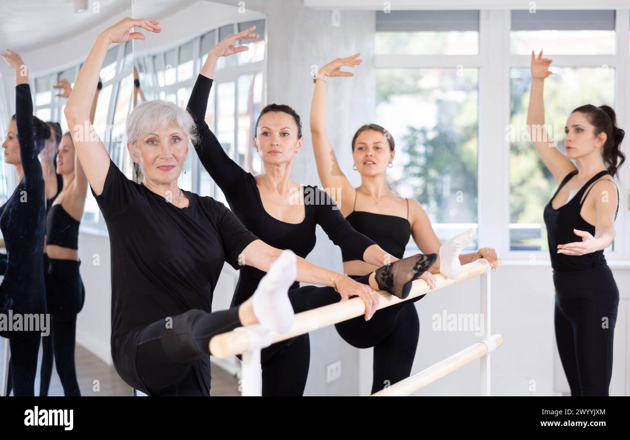 Group of female ballet dancers learn grand batman under guidance of an ...