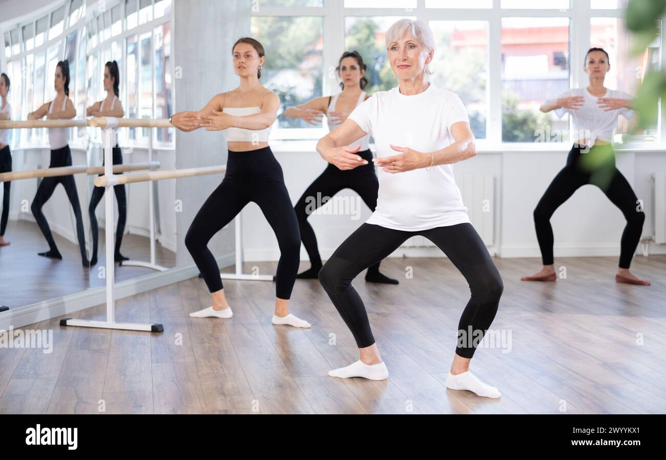 Girls in ballet class perform composition with grand plie with ...