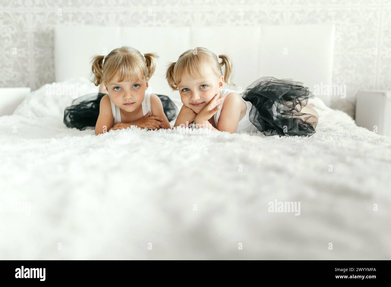 Two young girls are laying on a bed, laughing joyfully together Stock ...