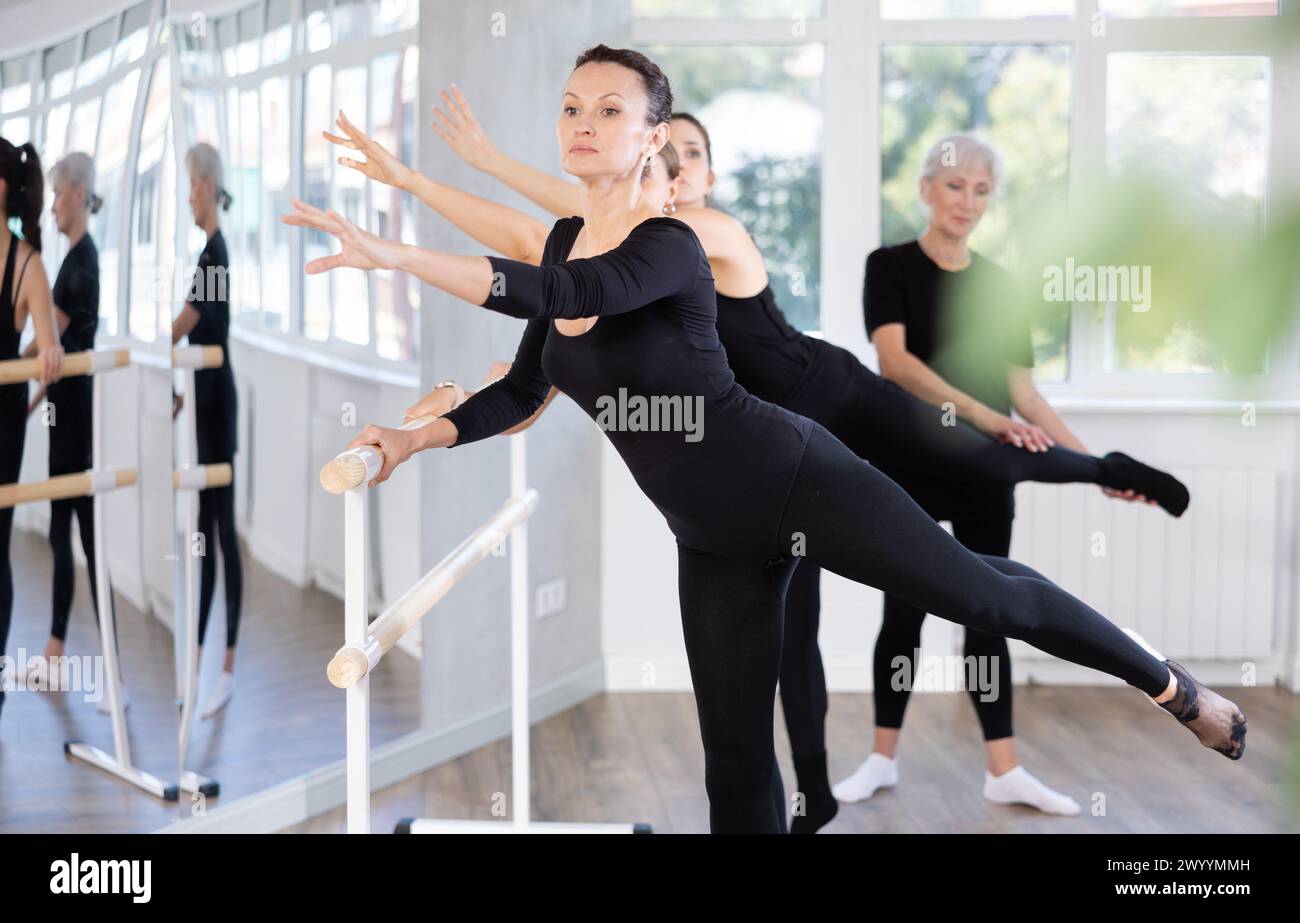 Woman performing arabesque at barre during group ballet class Stock ...