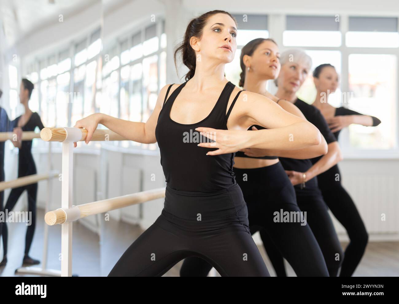 Fit brunette practicing demi plie at barre at ballet class Stock Photo ...