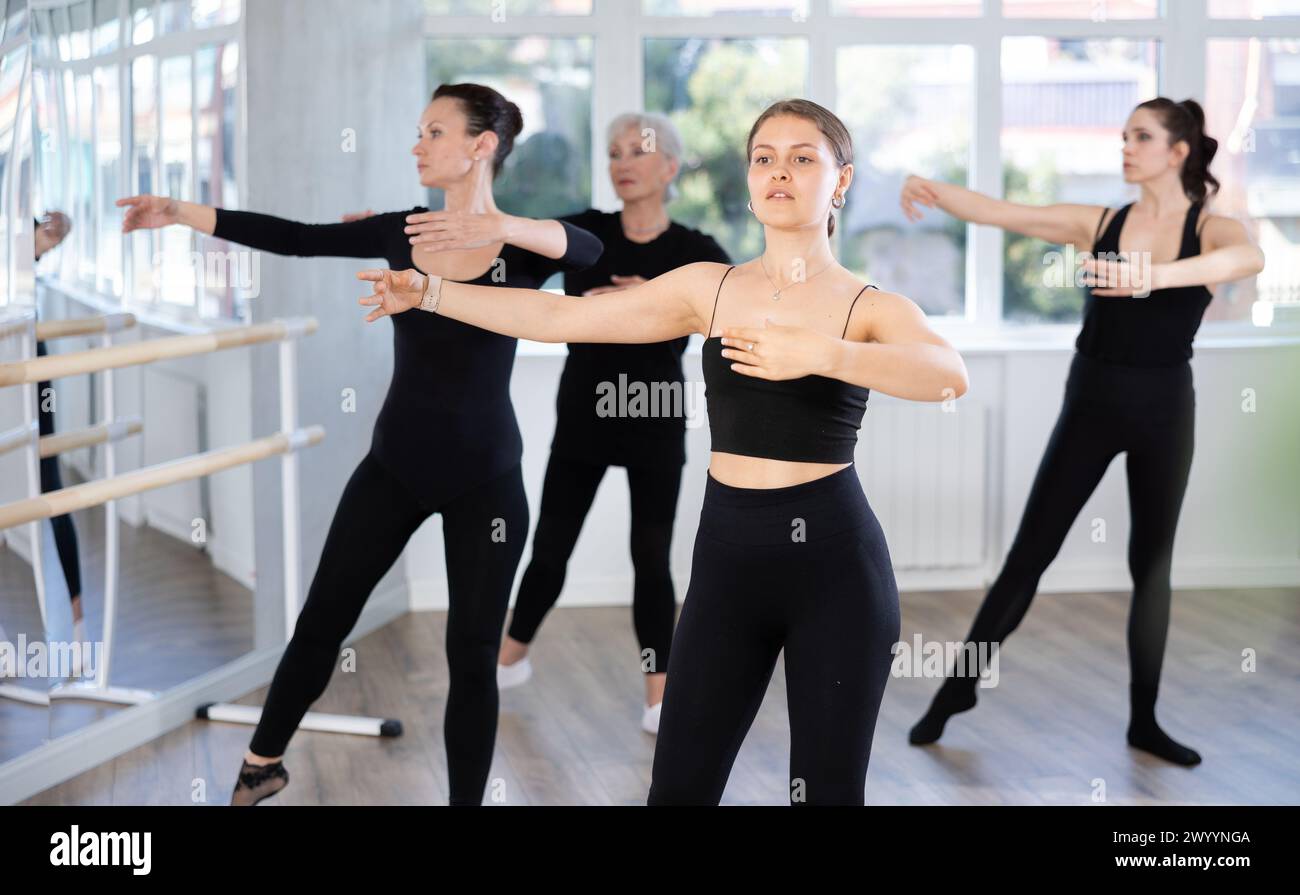 Young woman in group lesson with students rehearses, practices ballet ...