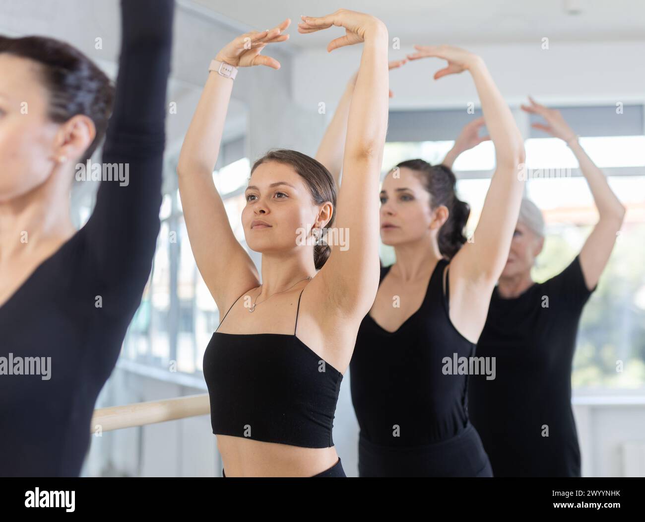 Women engaging in ballet at ballet barre in fourth position in training ...