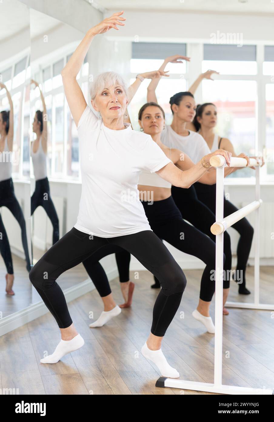 Group of dancers standing in grand plie ballet position in fitness room ...