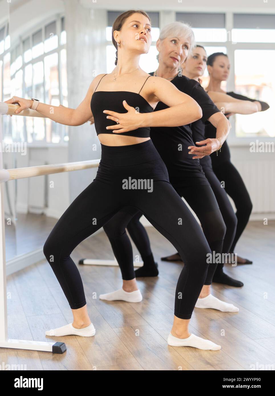 Girls in ballet class perform composition with grand plie with ...
