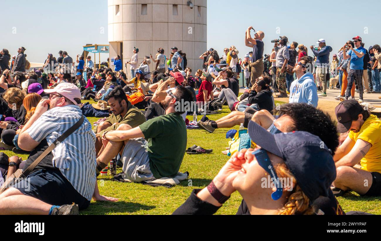 A crowd of people watching the 2024 solar eclipse sitting on the lawn ...