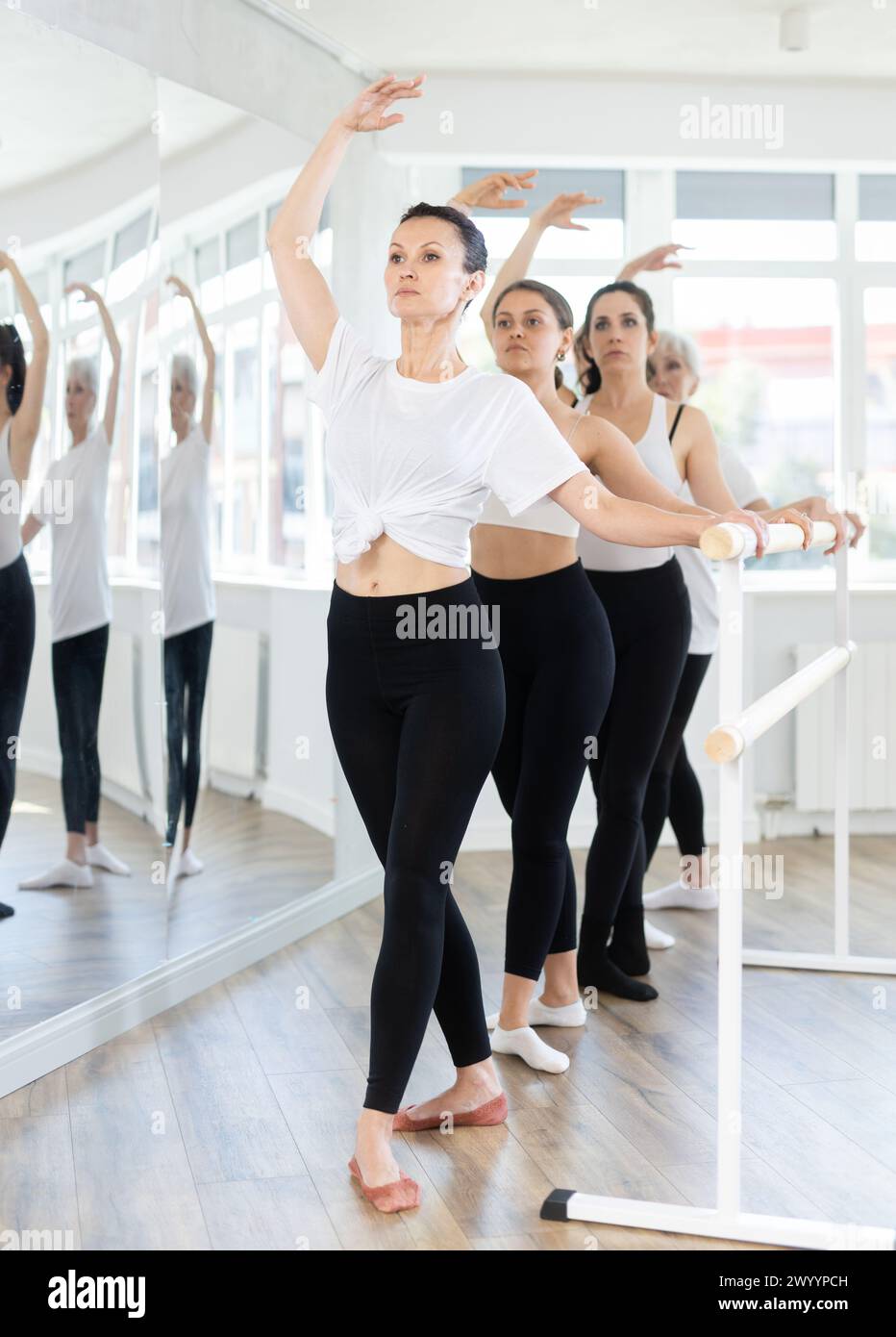 Woman mastering third position at ballet barre with group Stock Photo ...