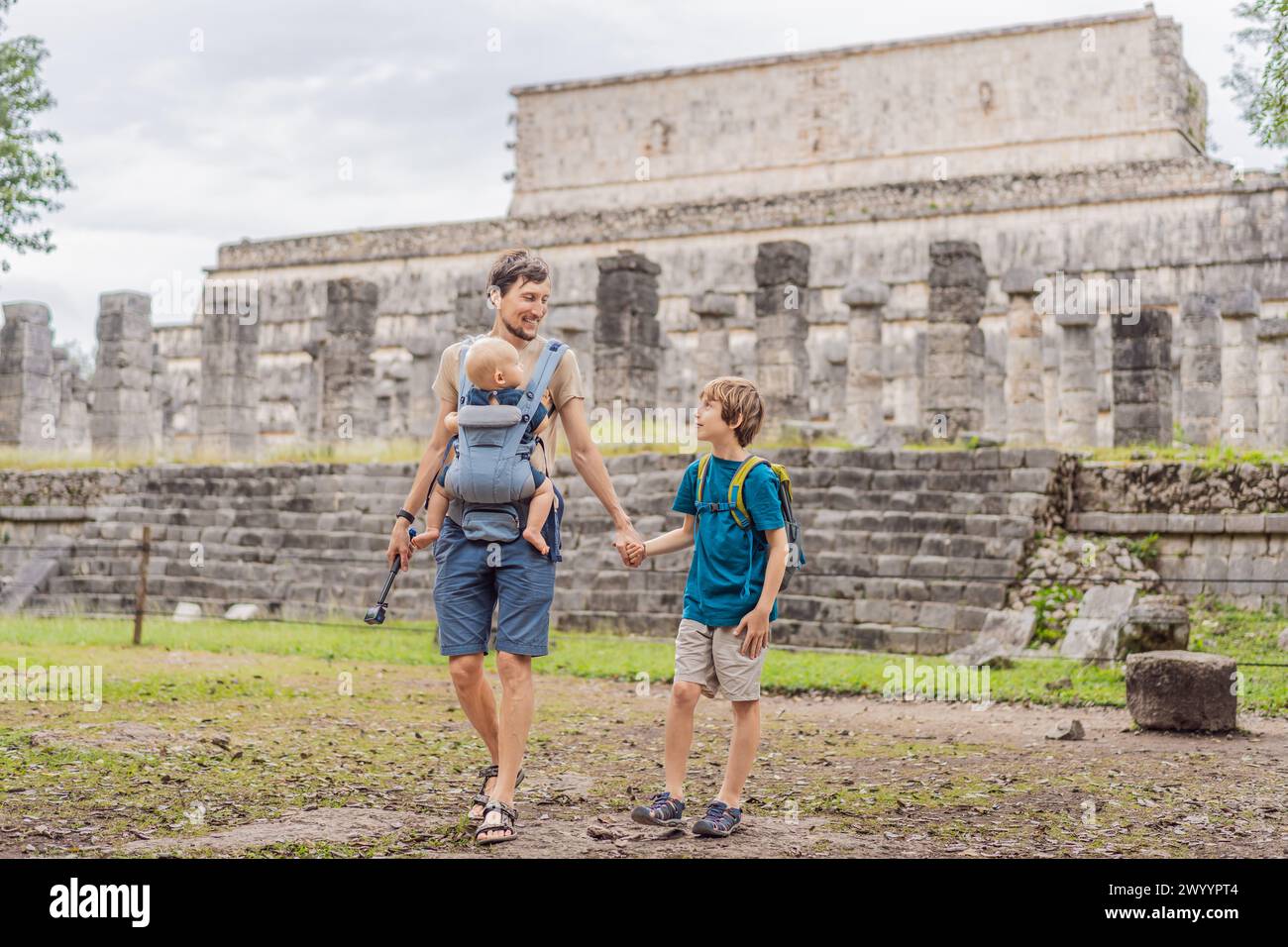 Father and two sons tourists observing the old pyramid and temple of ...