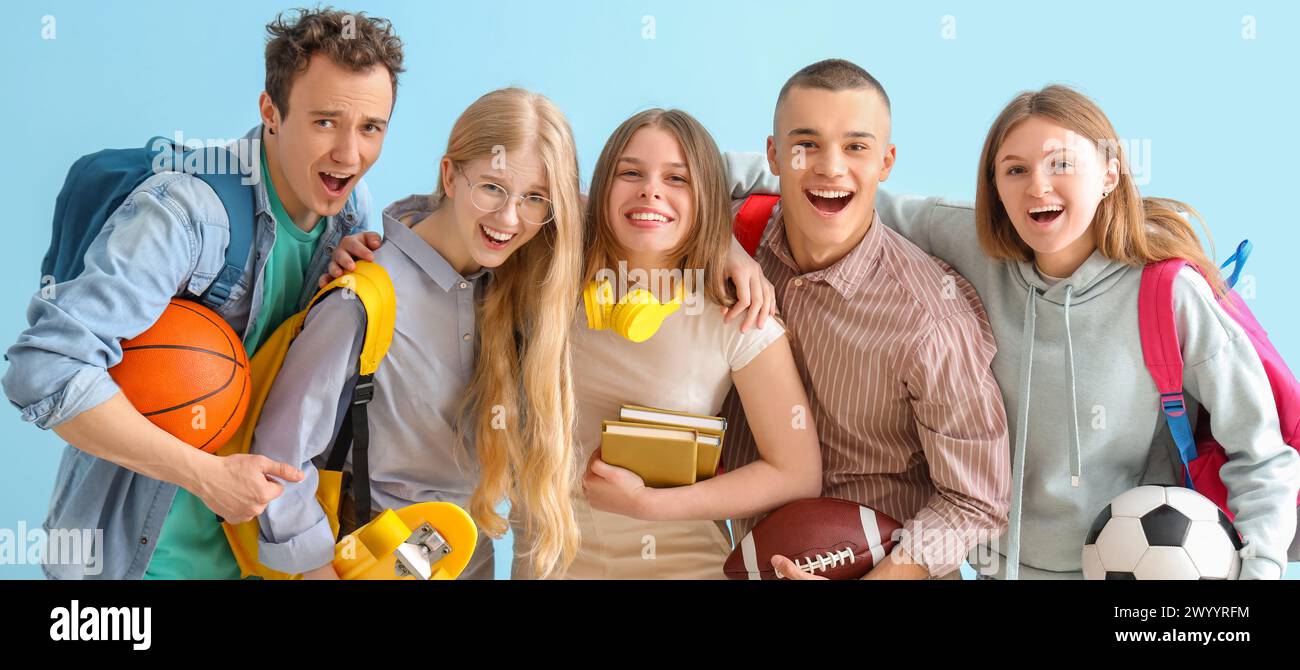 Group of happy students with backpacks on light blue background Stock ...