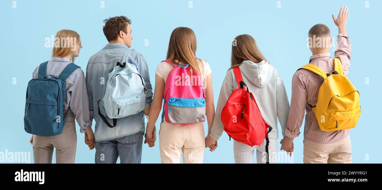 Group of students with backpacks on light blue background, back view ...