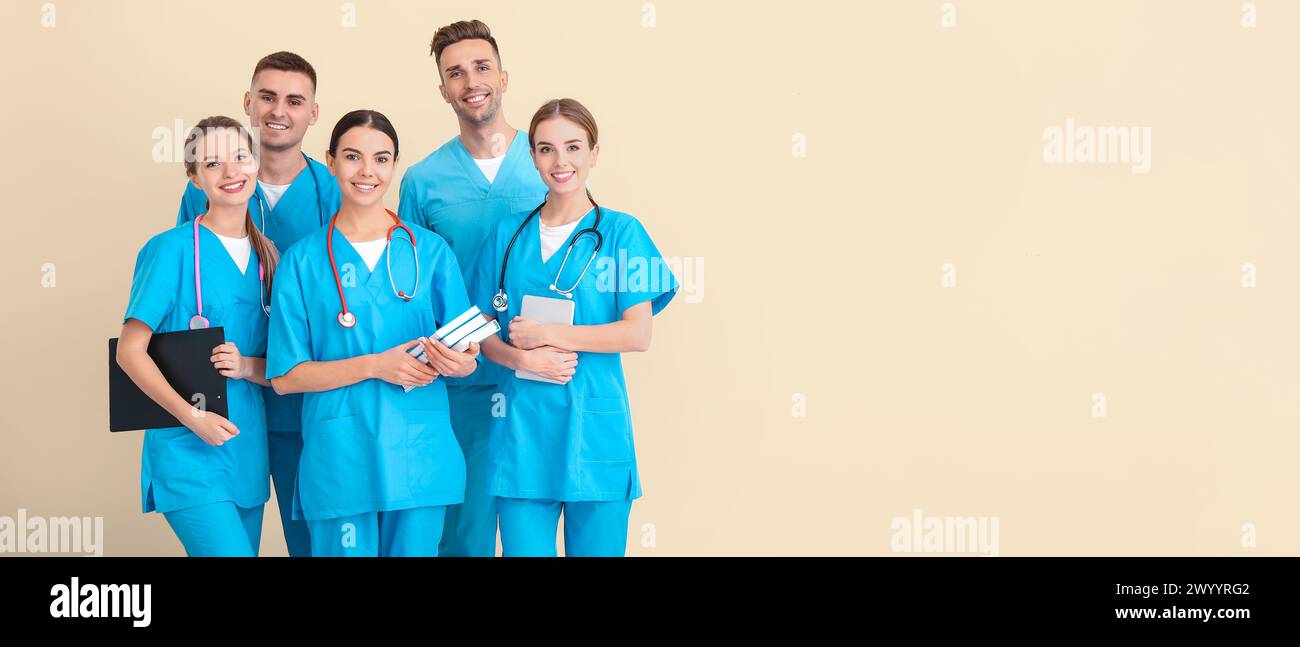 Group of happy medical students on beige background with space for text ...