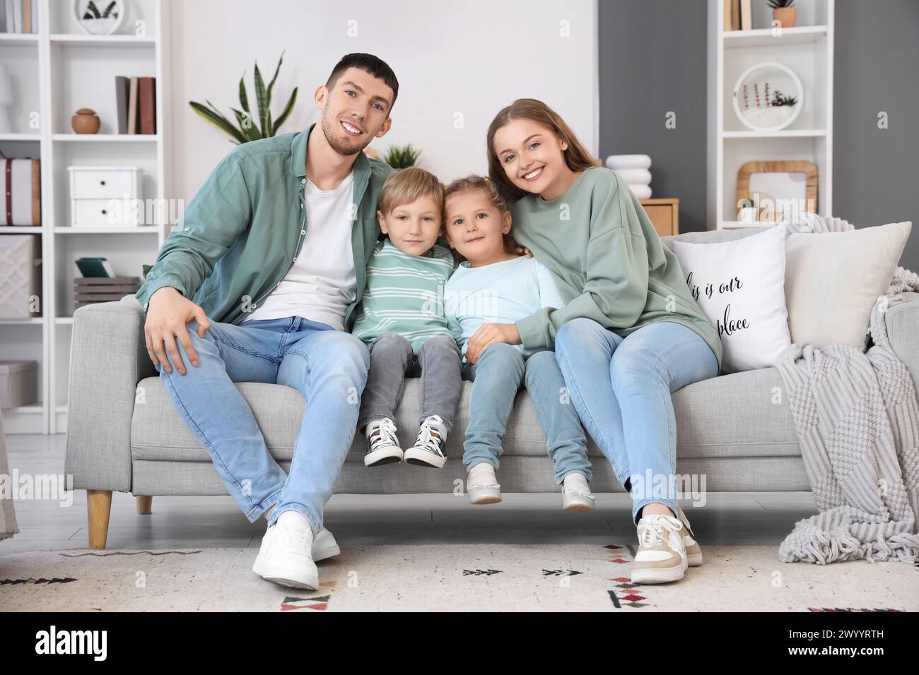 Little children with their parents sitting on sofa at home Stock Photo ...