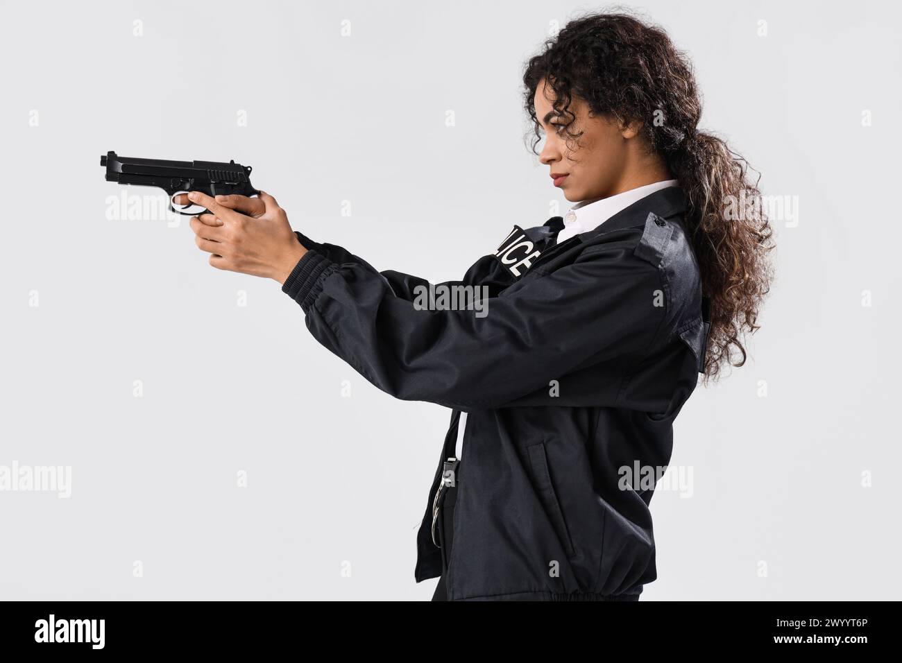 African-American female police officer with gun on white background ...