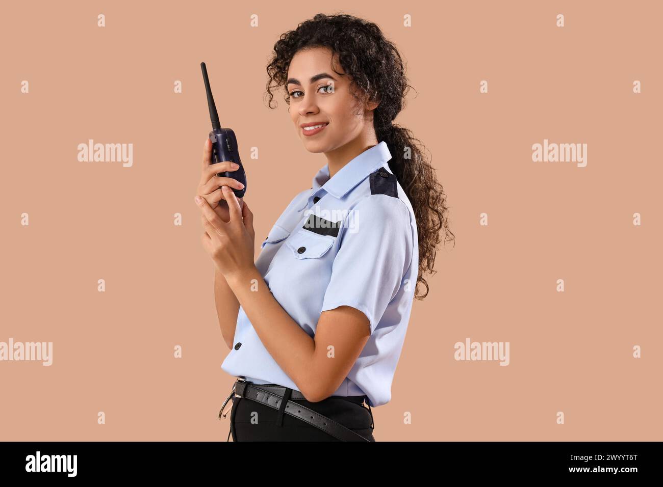 African-American female police officer with radio transmitter on brown ...