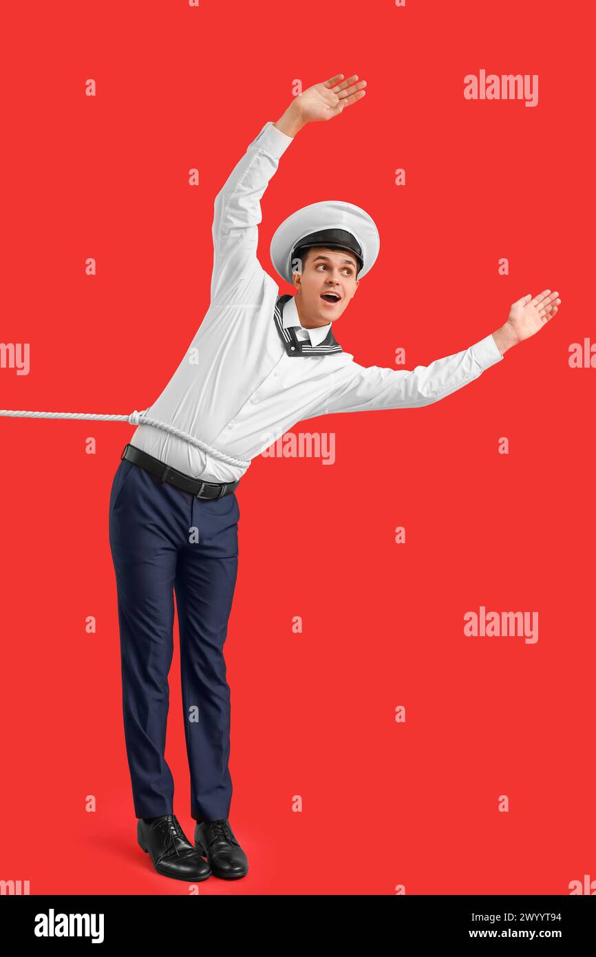 Young sailor with rope on red background Stock Photo - Alamy