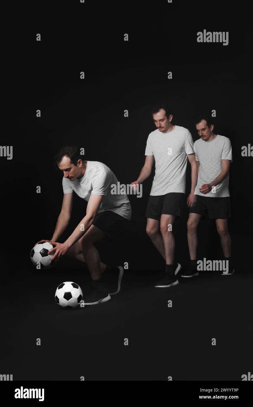 Young man in football uniform playing with ball in motion on black ...