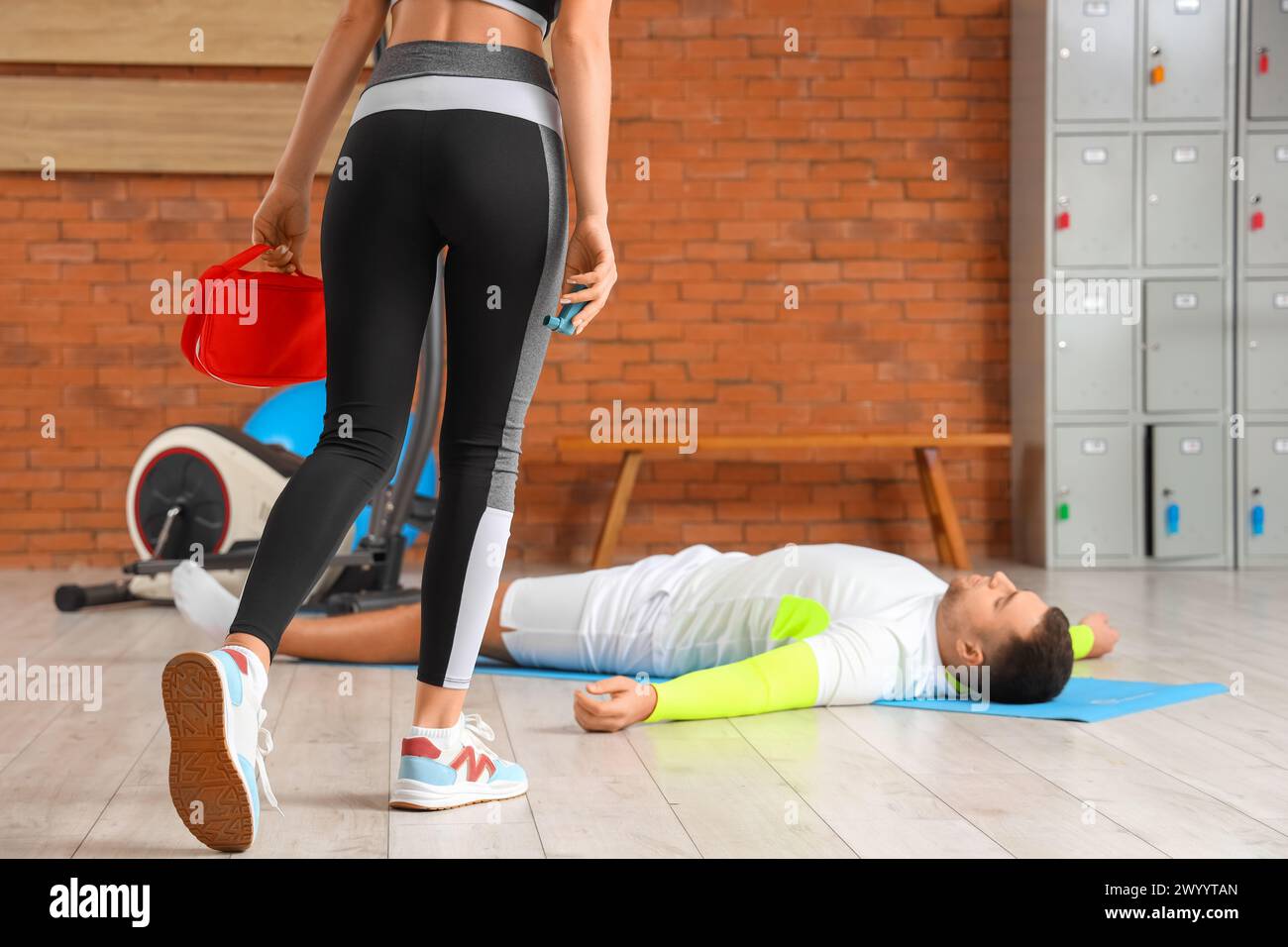 Female trainer with inhaler and first aid kit walking to lying man in ...
