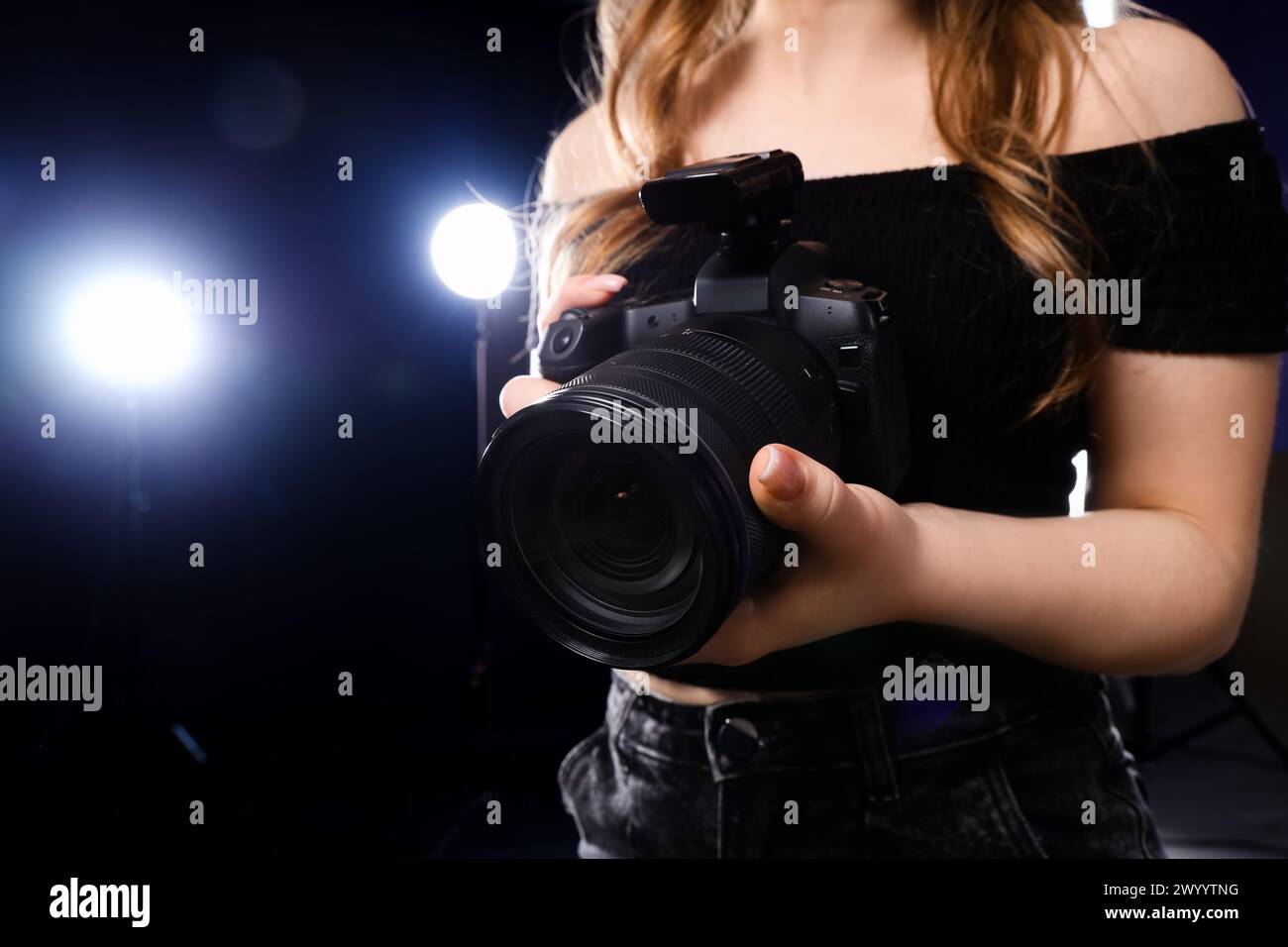 Female photographer with modern camera and spotlight backlighting on ...