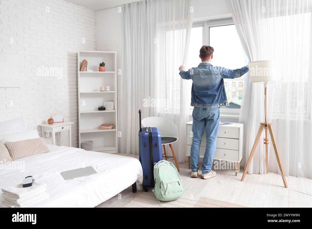 Male tourist opening curtains in hotel room, back view Stock Photo - Alamy